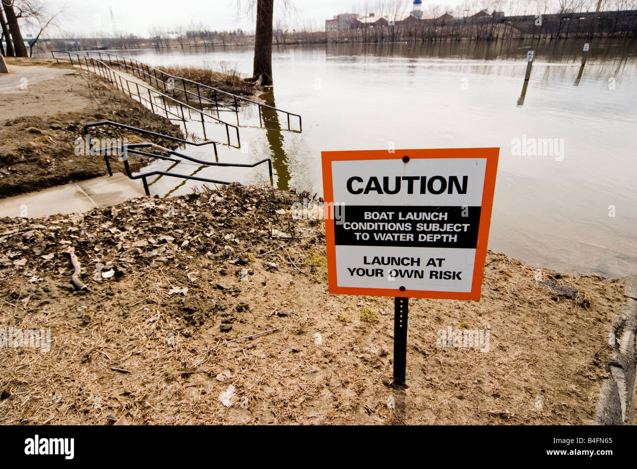 CAUTION sign near a boat launch at an overflowing river Stock Photo - Alamy