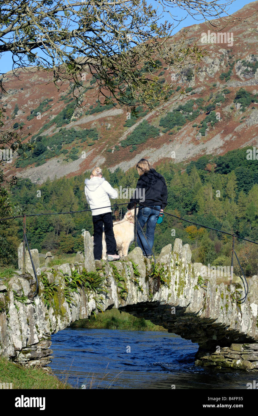 Walkers crossing Slater Bridge over the River Brathay in Little ...
