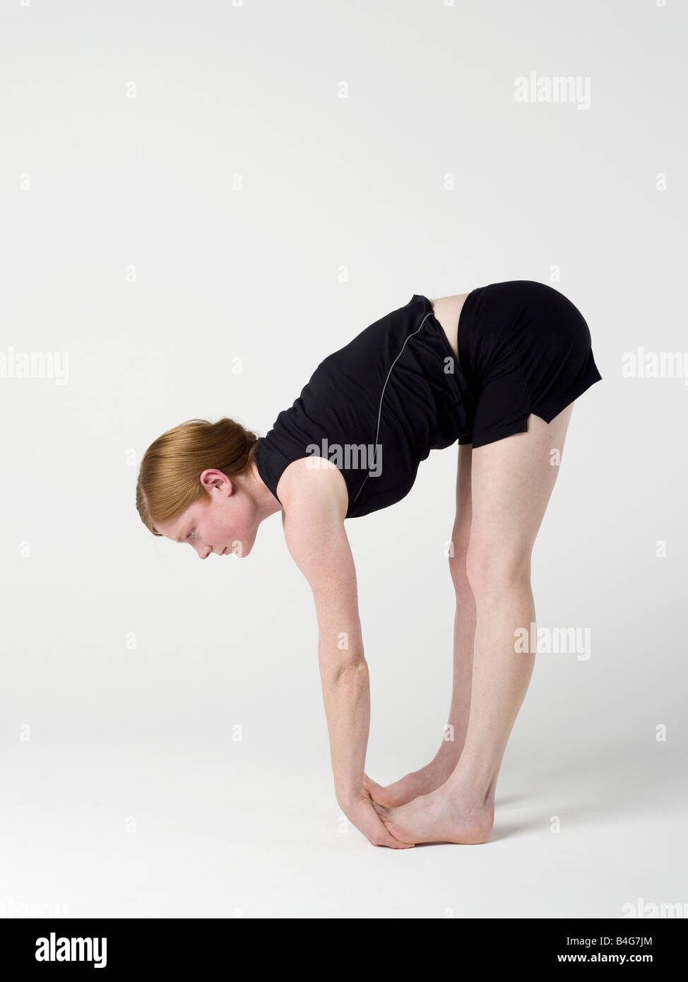 A young woman practicing the 'Upward Forward Fold' yoga pose Stock ...