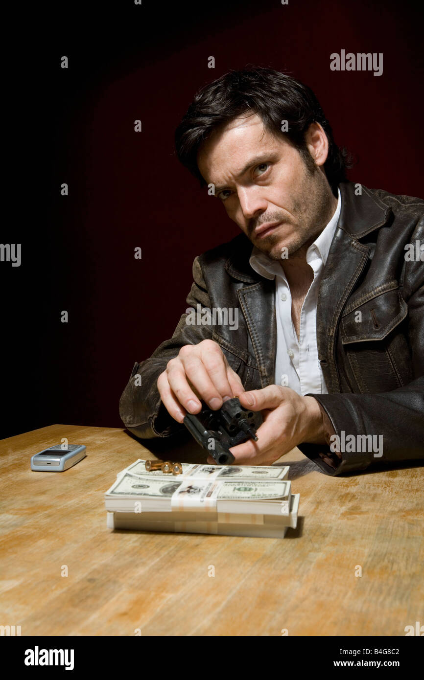 A man loading a gun with bullets next to several stacks of money Stock ...
