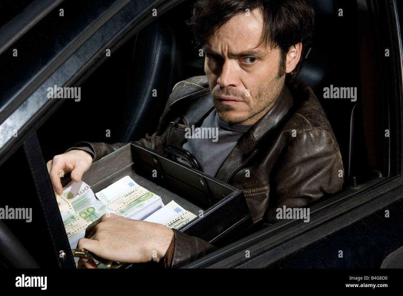 A man sitting in a car with an open briefcase full of money Stock Photo ...