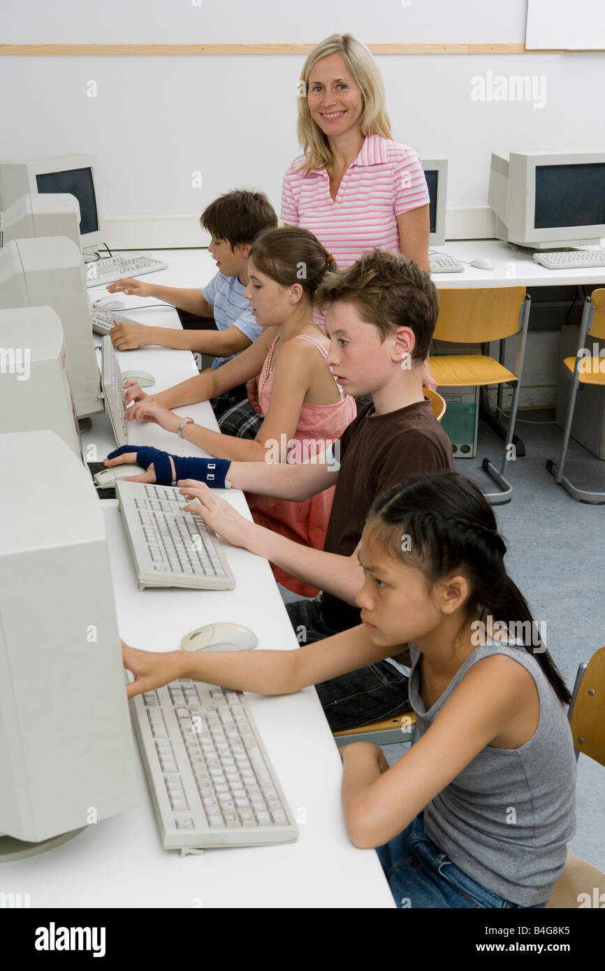A teacher and four pre-adolescent children in a computer lab Stock ...