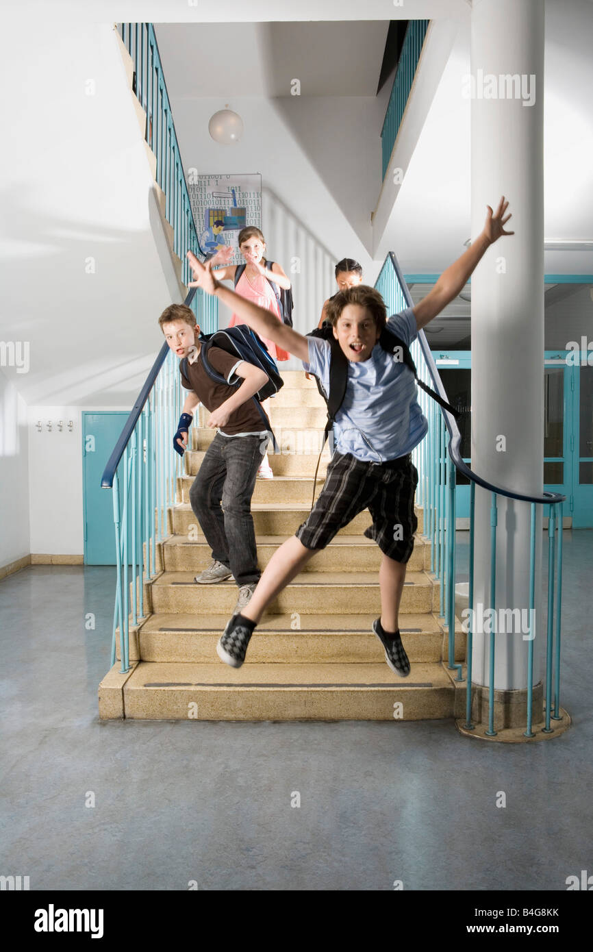 Four pre-adolescent children running down stairs excited Stock Photo ...