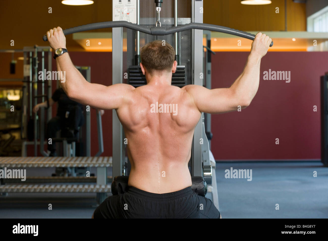 A weightlifter using a lateral pull-down weight machine Stock Photo - Alamy