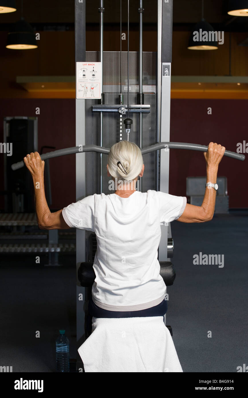 A senior woman using a lateral pull-down weight machine Stock Photo - Alamy