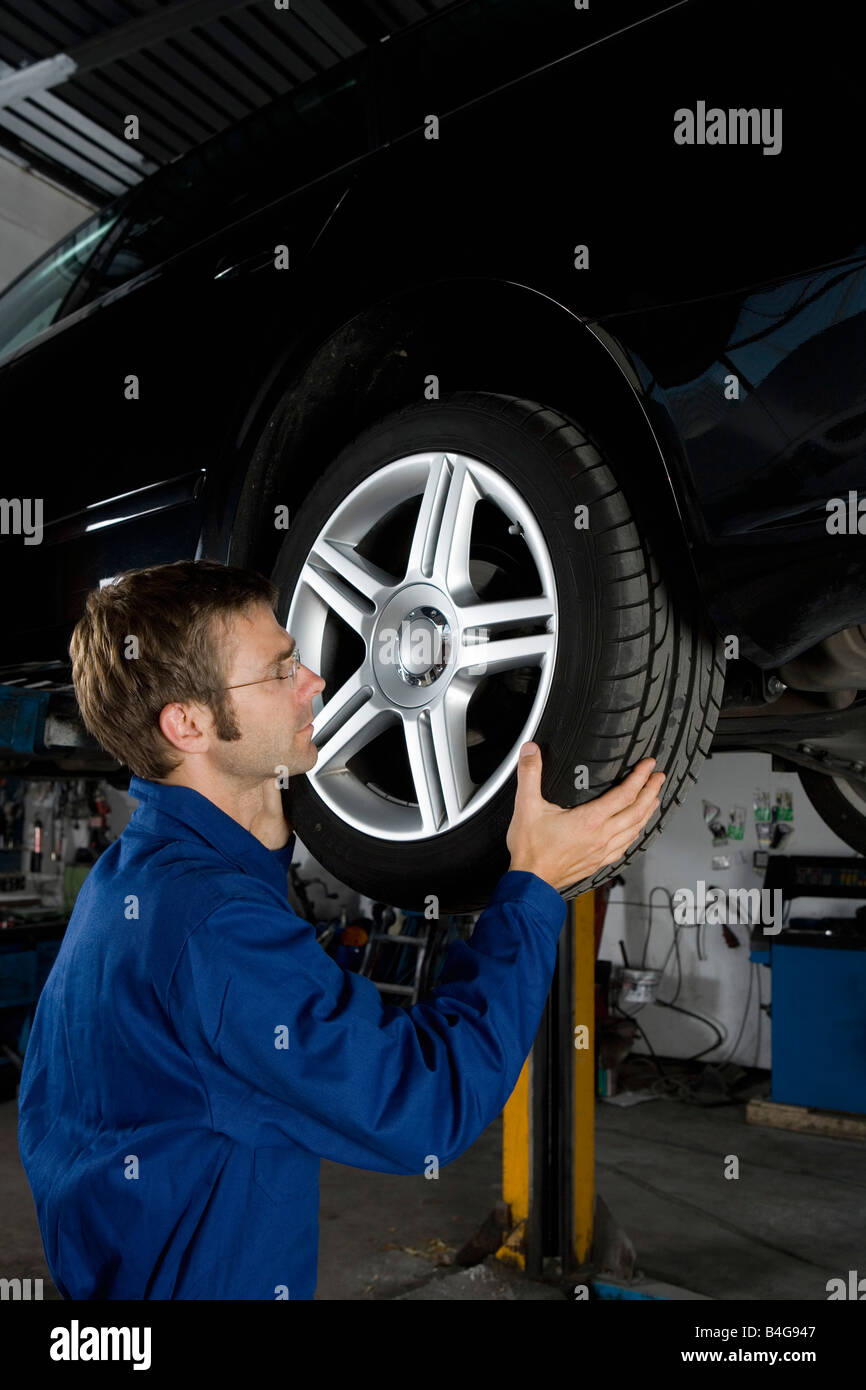 A mechanic fixing the wheel of a car in a repair garage Stock Photo - Alamy