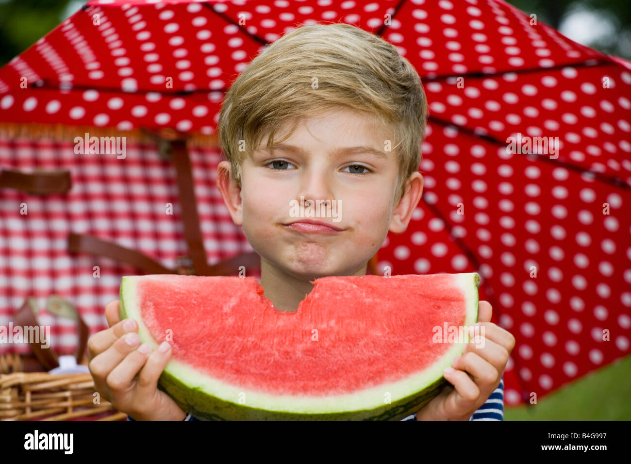 A young boy holding a slice of watermelon with a bite missing Stock ...
