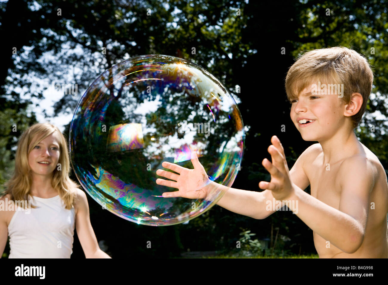 Two children trying to catch a bubble Stock Photo - Alamy