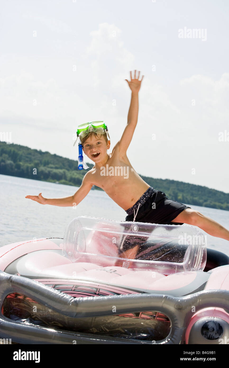 A young boy standing in an inflatable raft on a lake Stock Photo - Alamy