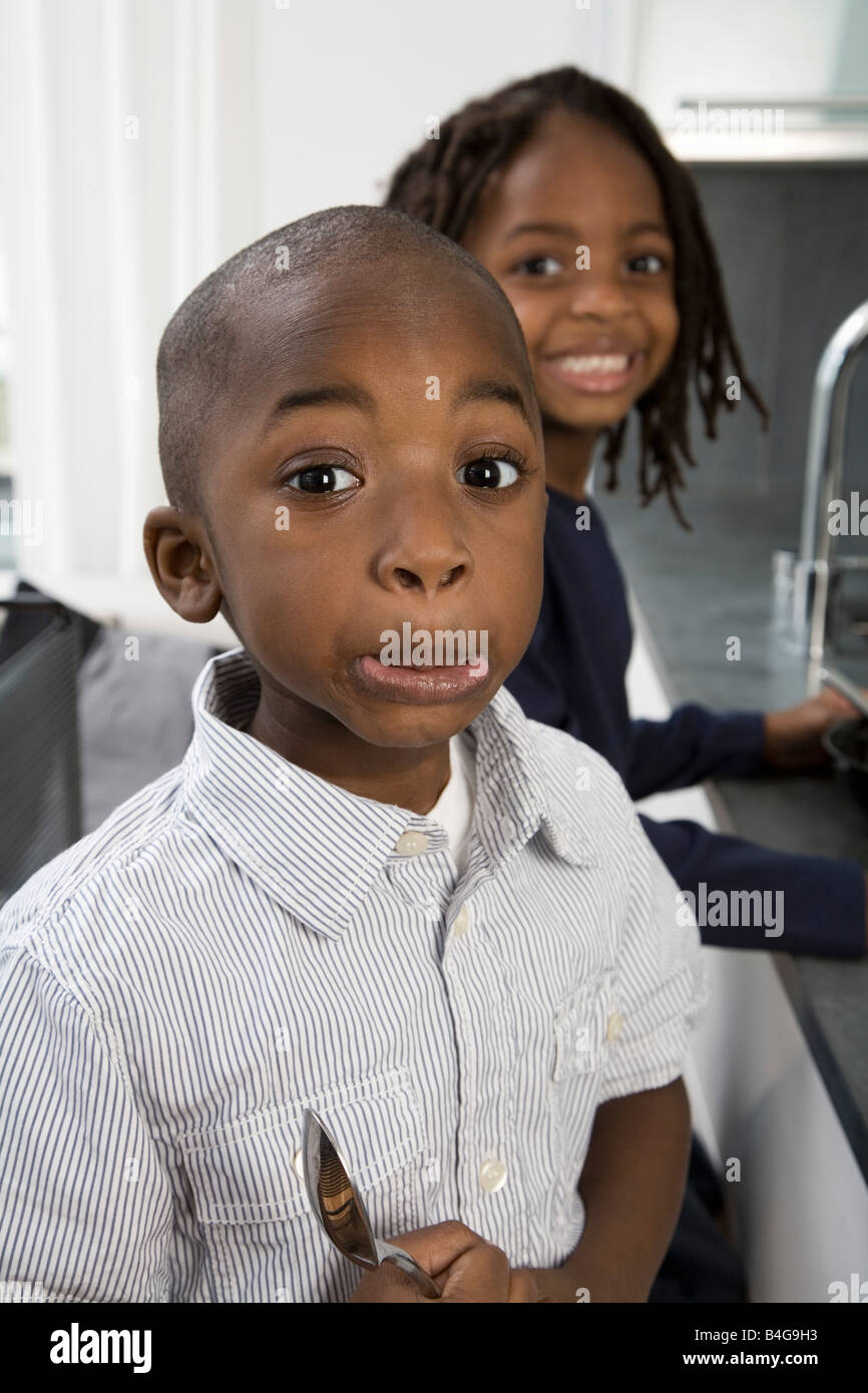 A young boy making a funny face while his brother smiles behind him ...