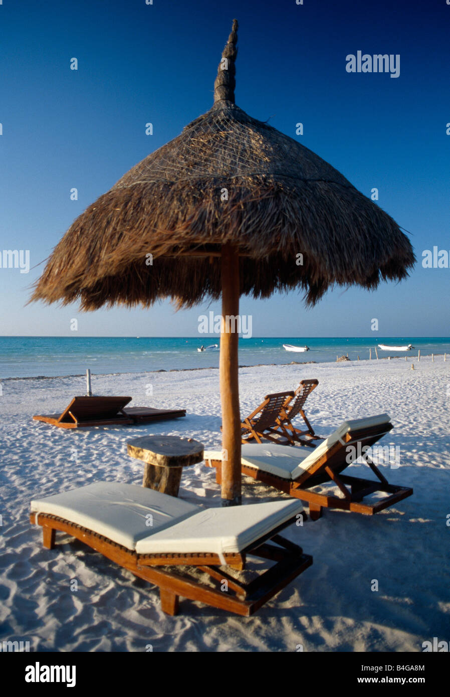 Sun loungers and straw parasol on a beach Stock Photo - Alamy