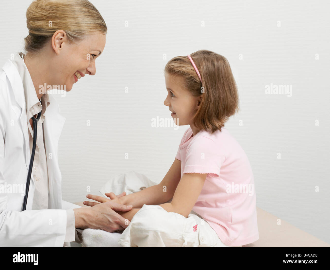 A girl on an exam table facing a pediatrician and smiling Stock Photo ...