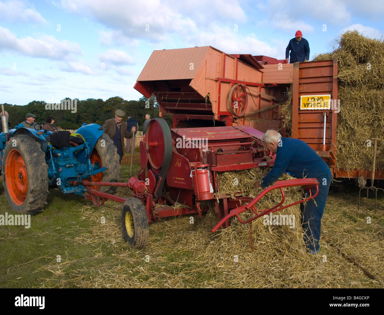 Elderly farm workers using a threshing machine at a demonstration of ...