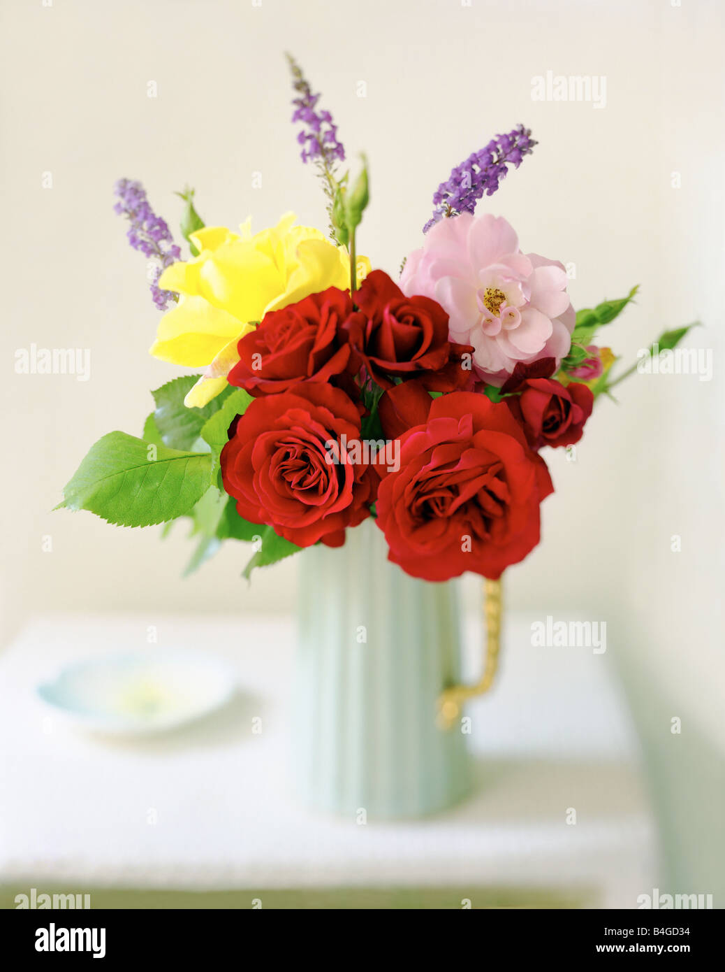 pink yellow and red roses in blue jug on a white table Stock Photo - Alamy