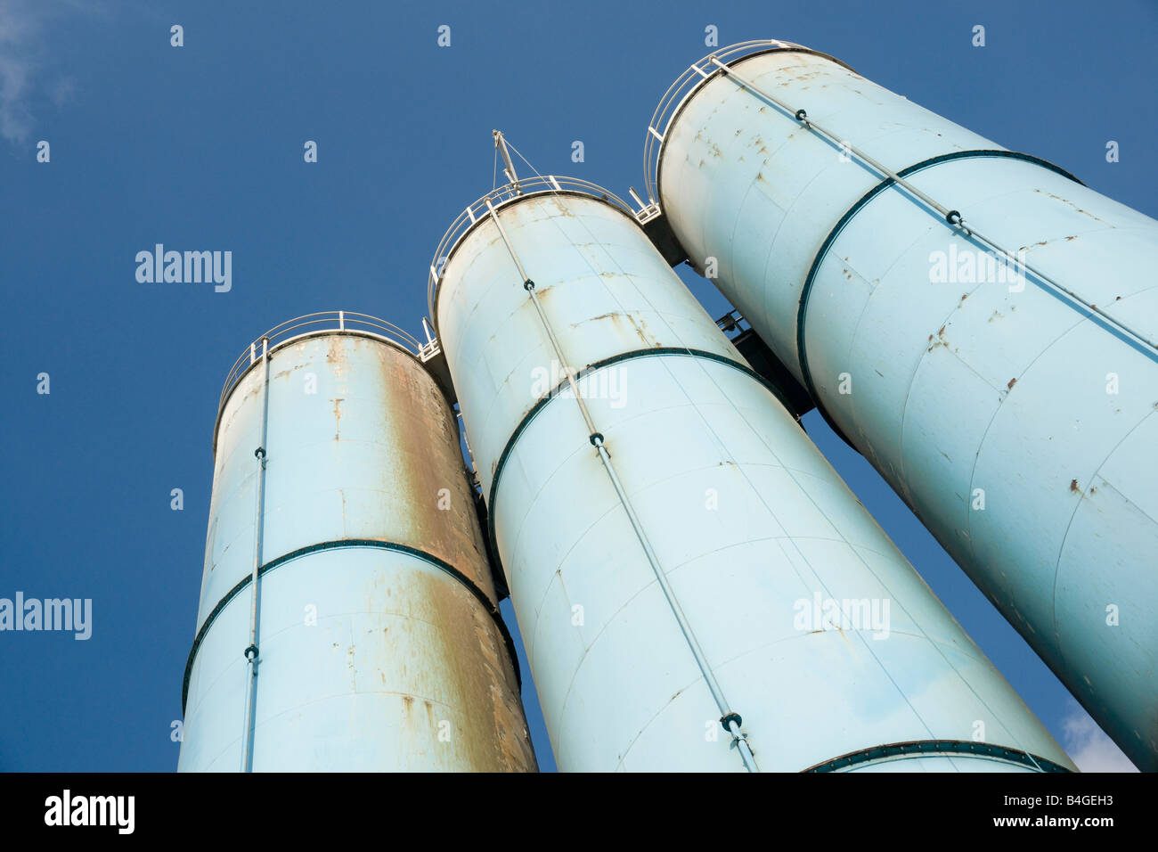 Three blue rusty industrial silos against deep blue sky Stock Photo - Alamy