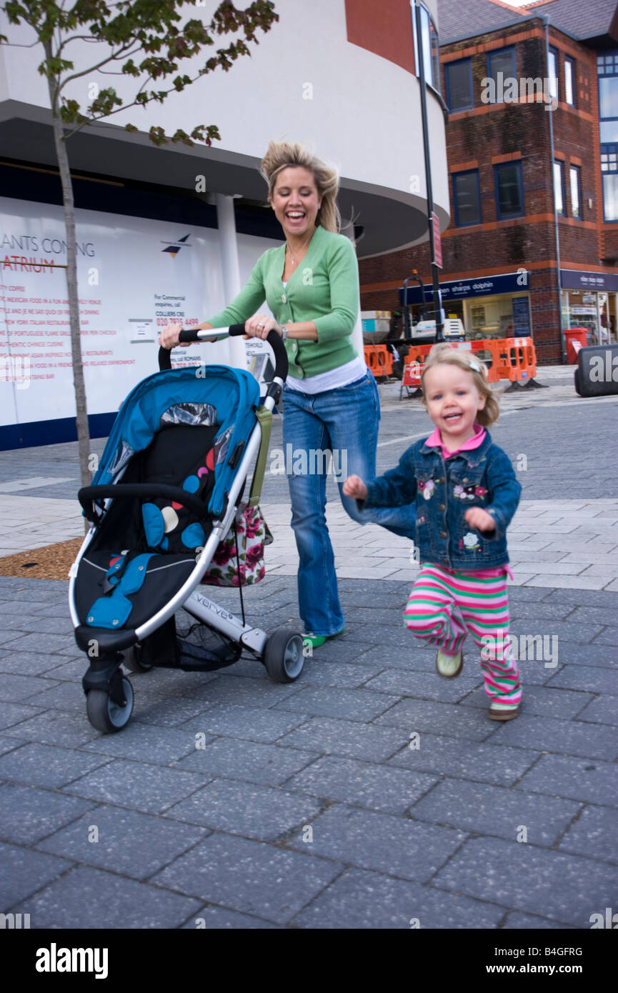 mother pushing a buggy with her little girl racing along at her side ...