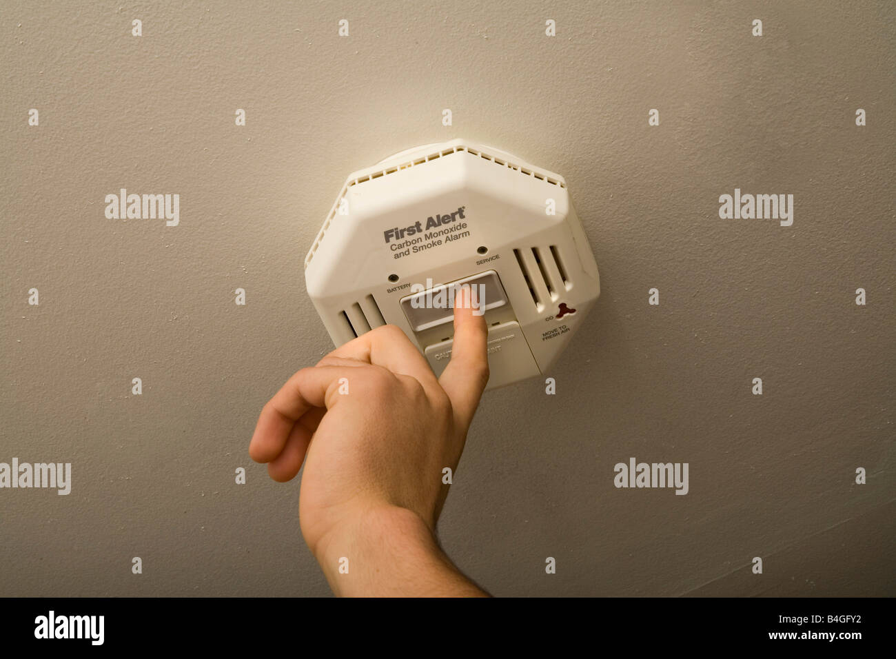Finger presses test button on home smoke detector Stock Photo - Alamy