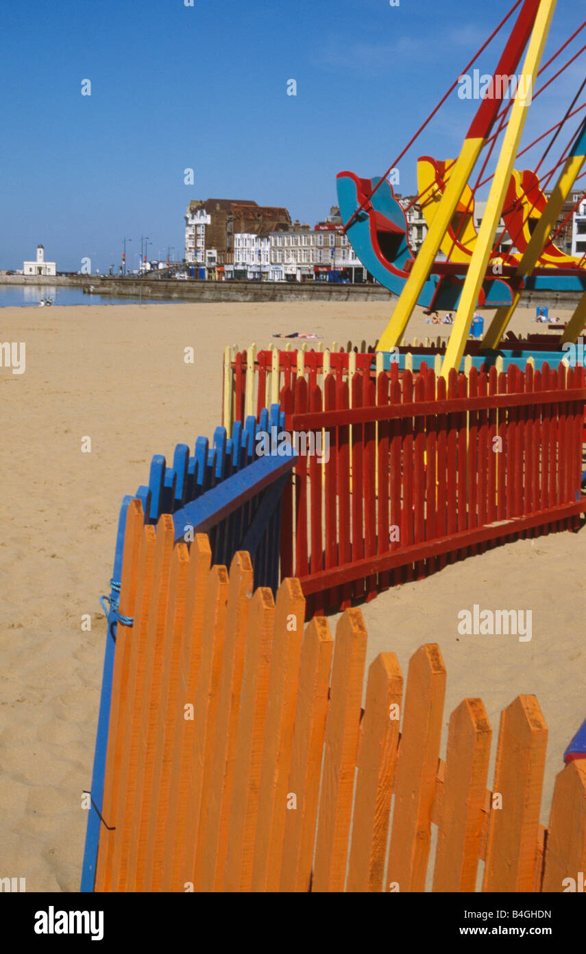 Brightly coloured wooden fence in front of swingboats at Fairground on ...