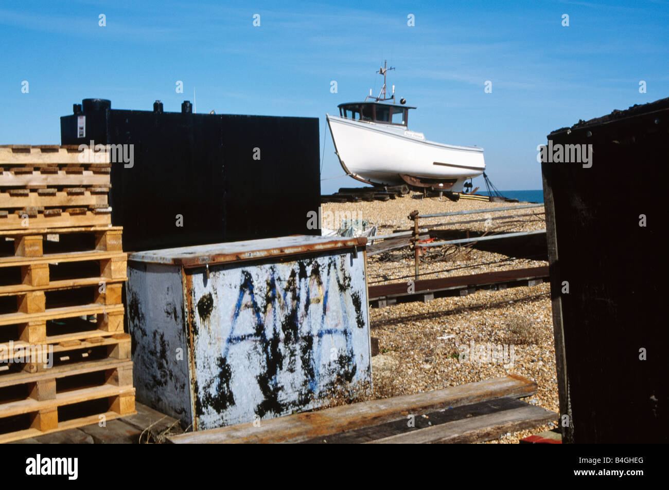 Wooden pallets and metal boxes on beach with white fishing boat at Deal ...