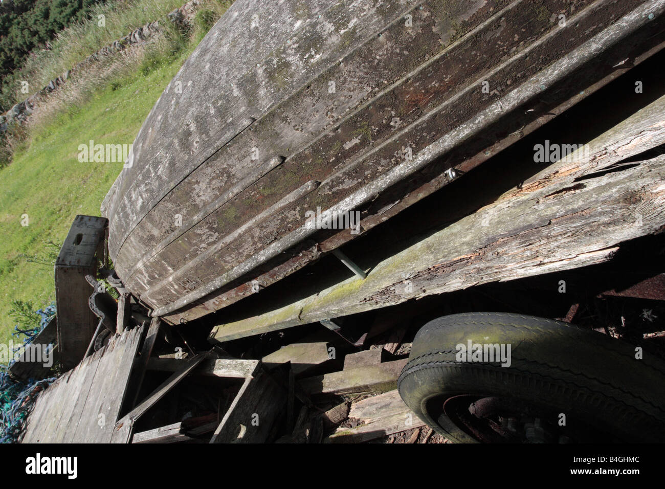 Upturned and rotting wooden boat on top of a similarly rotting trailer ...