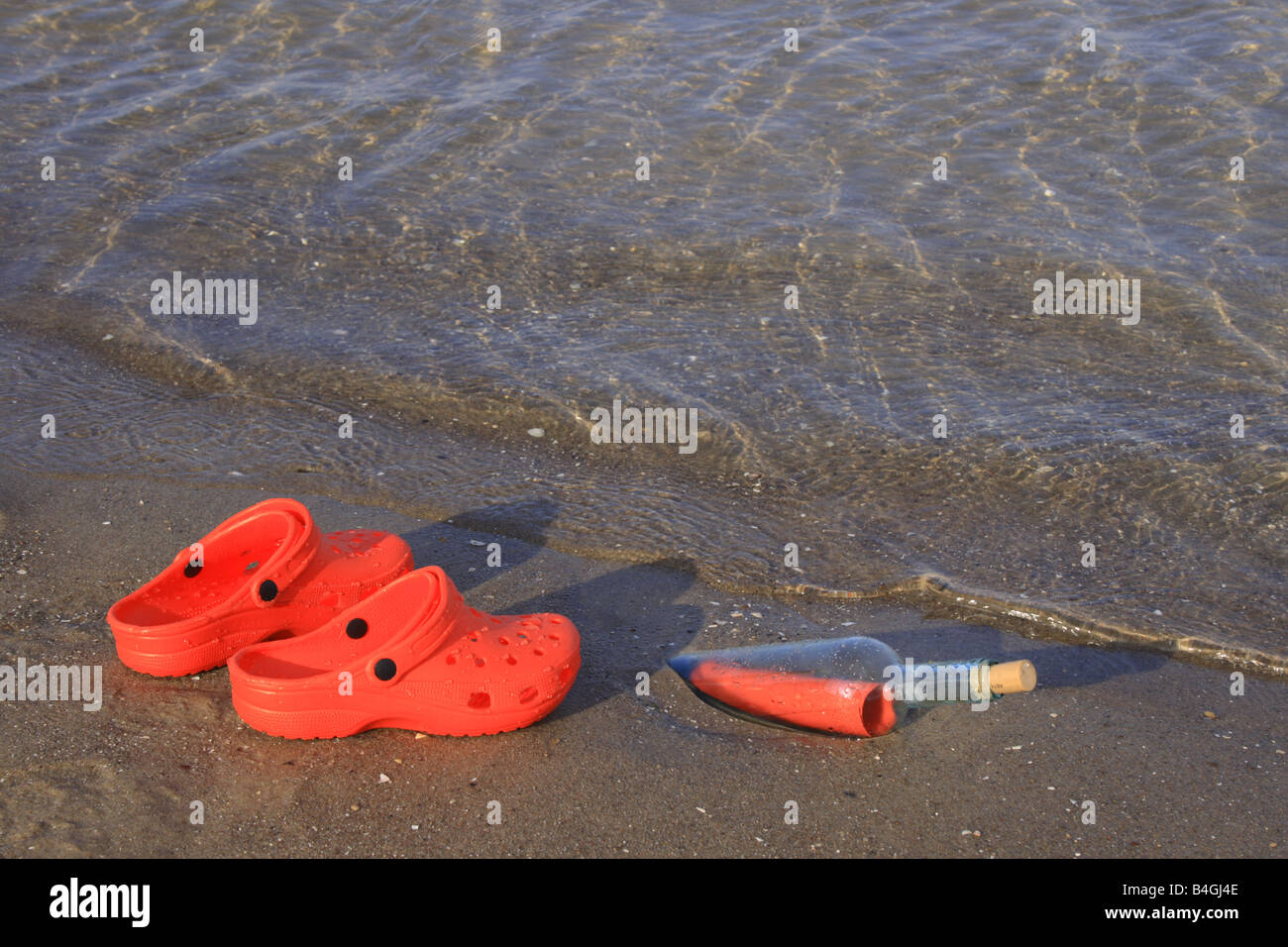 pair of red crocs and red letter as message in a bottle at a sandy ...