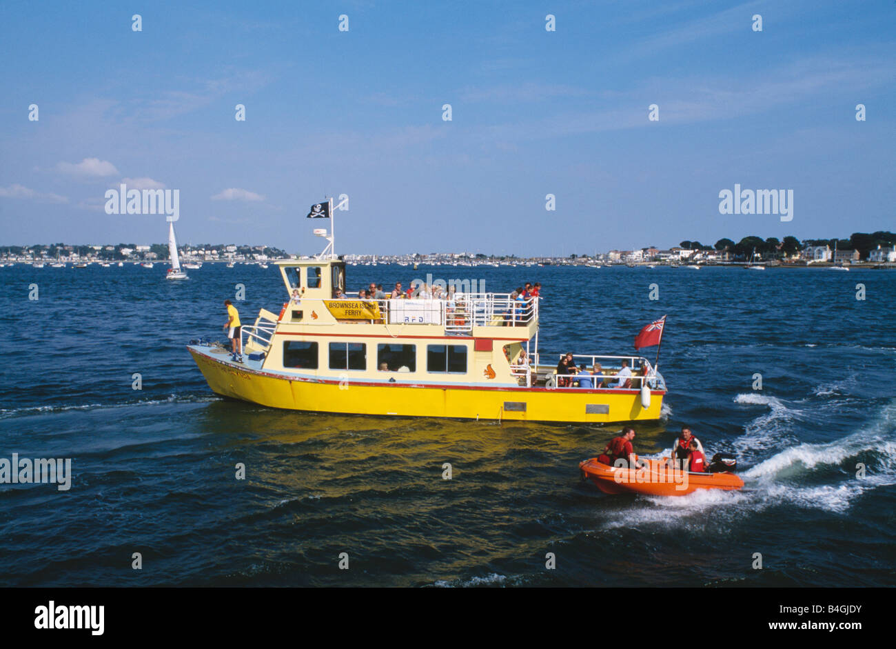 Yellow passenger boat beside orange speedboat on the water in Poole ...