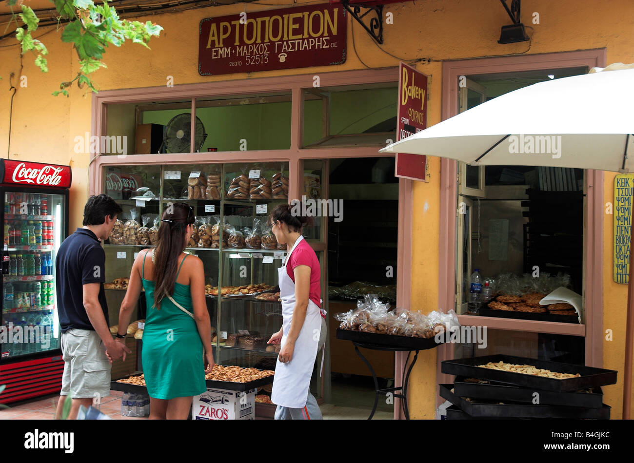 Young couple standing in front of bakery looking at display window with ...