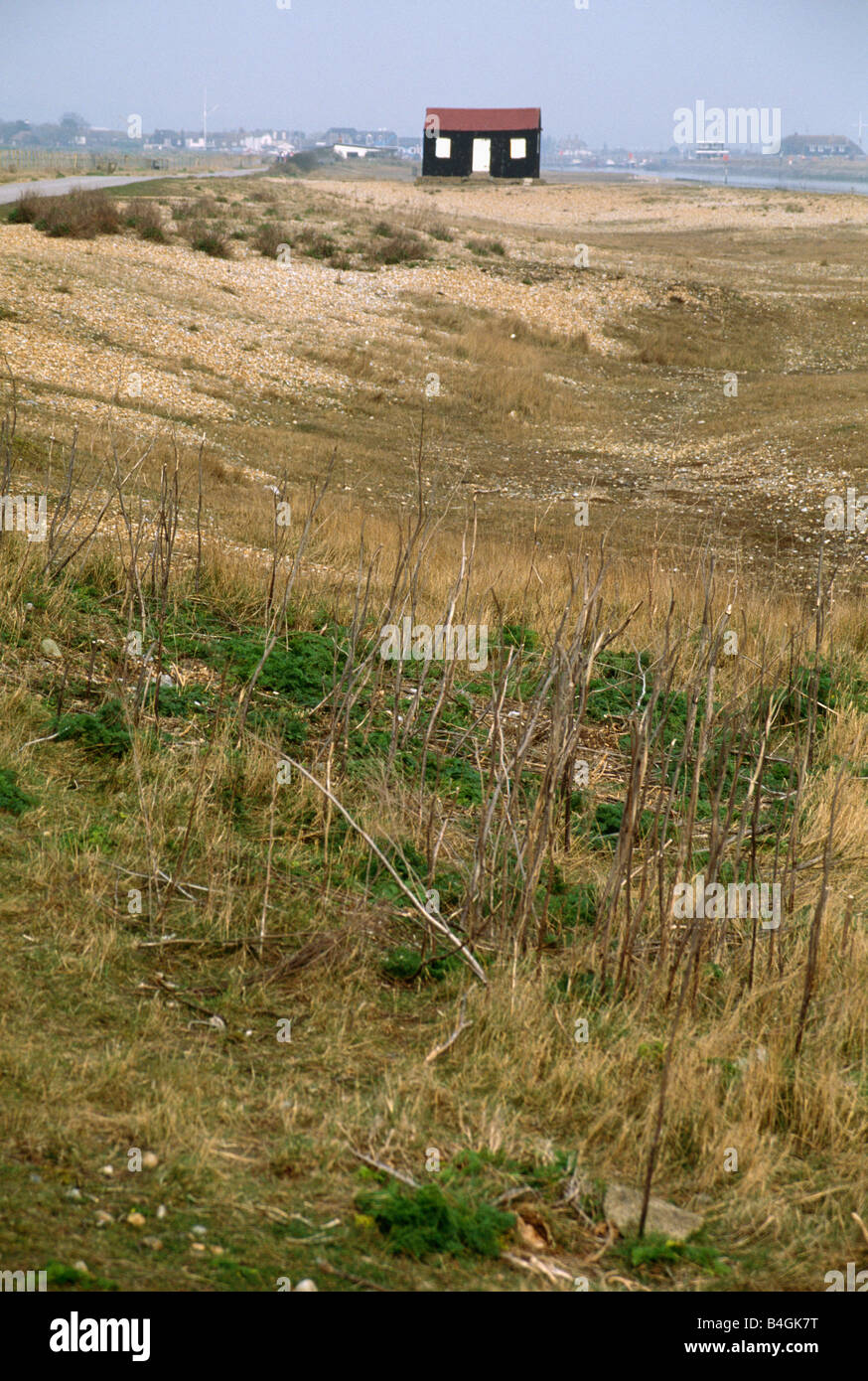 View across sandy land by the sea to black wooden hut with white ...