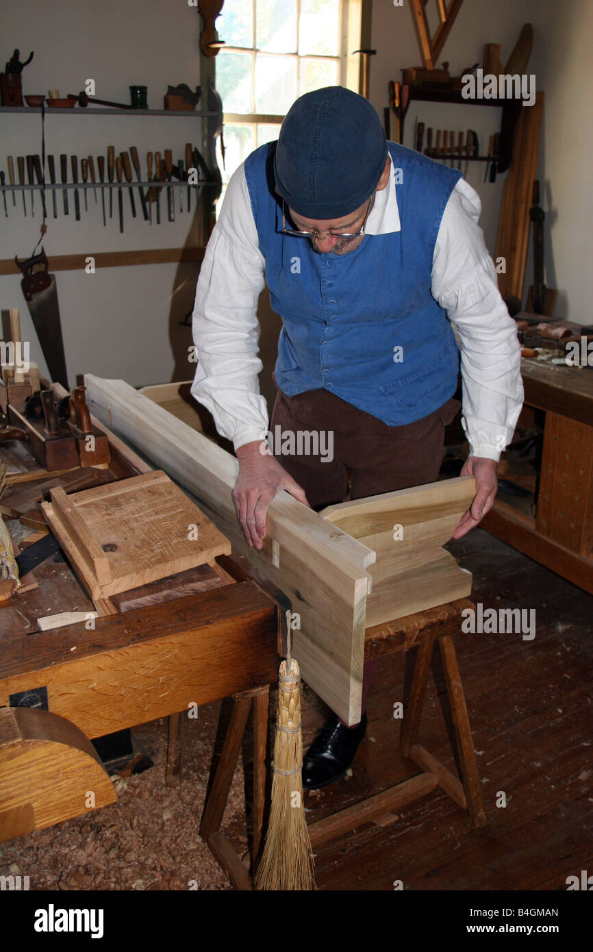 Male costumed interpreter showing joinery, building a wooden bench in ...