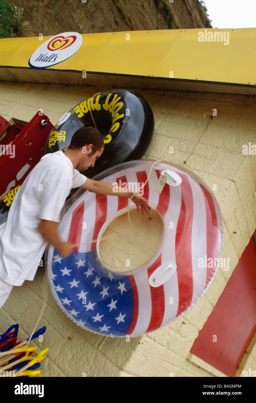 Man attaching large plastic swimming ring to the wall of seaside shop ...