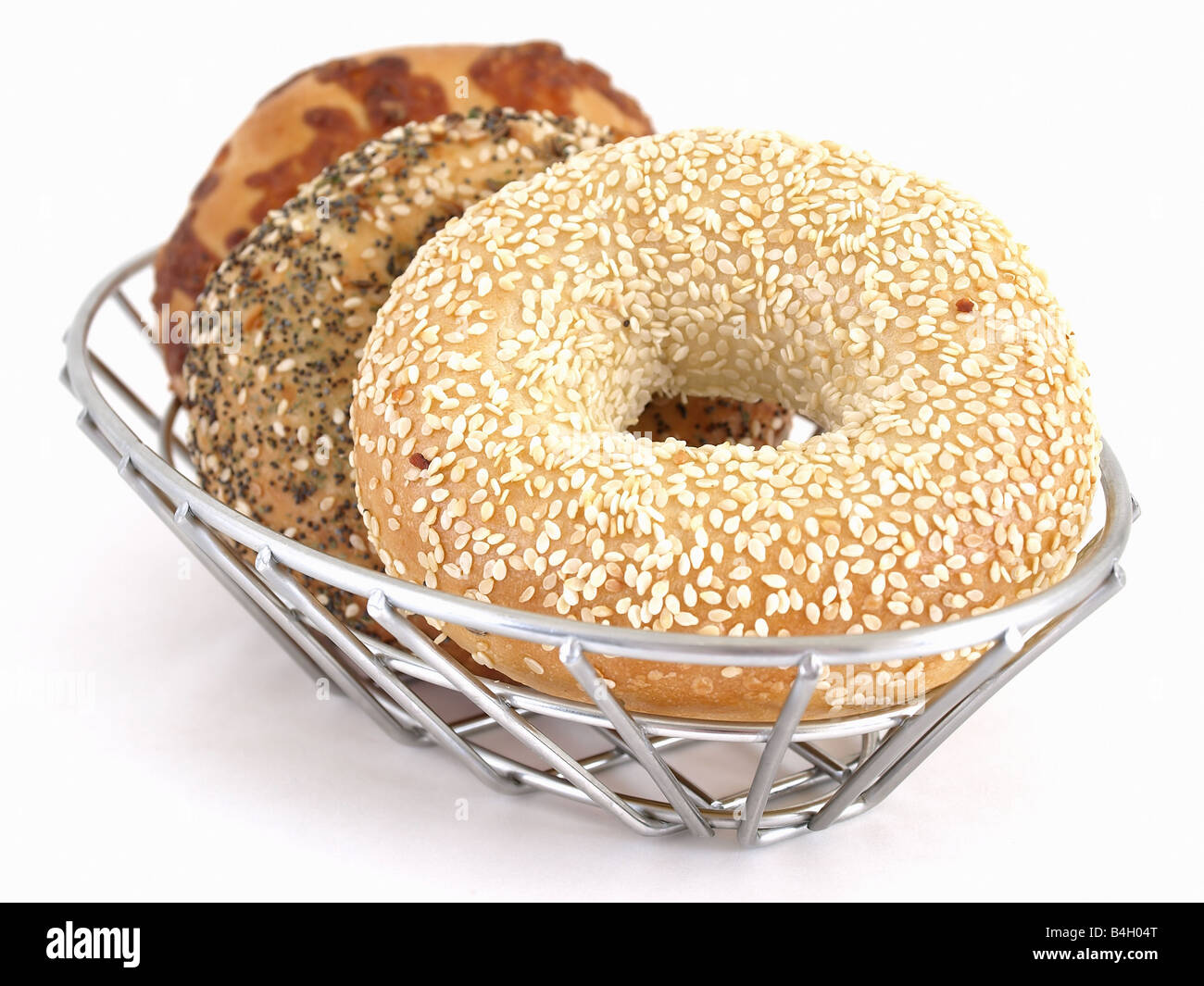 Fresh baked bagels in a wire basket isolated against a white background ...