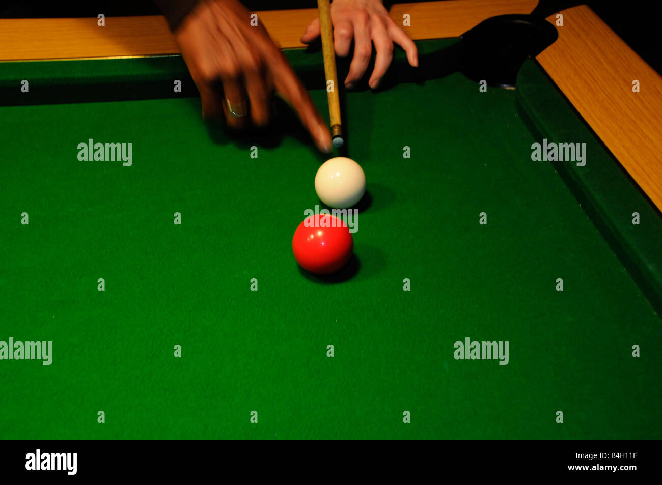 A game of pool with a pointing finger guiding a team mate pool player ...