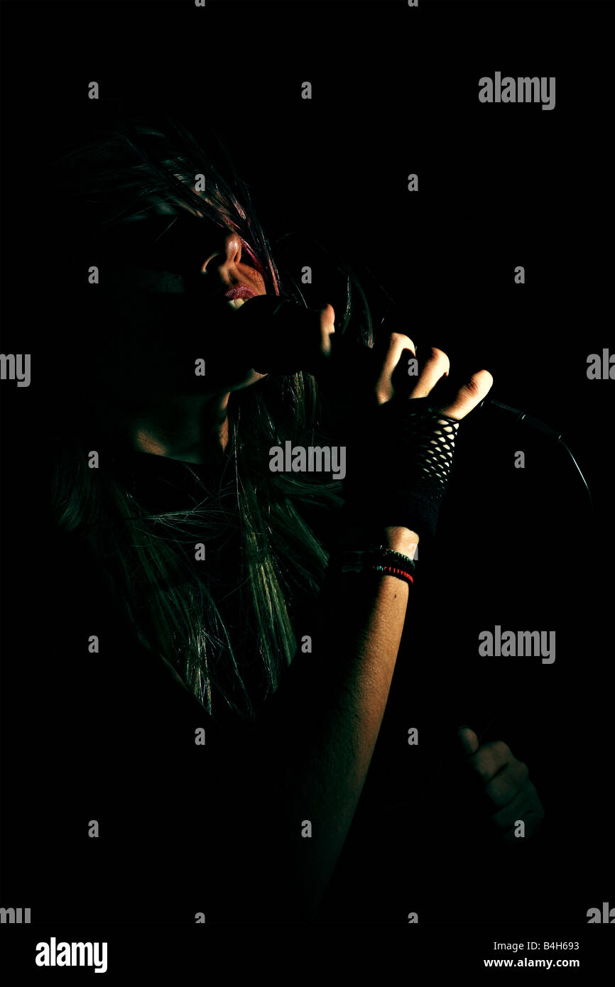 Blonde gothic singer wearing black, singing on stage with microphone ...
