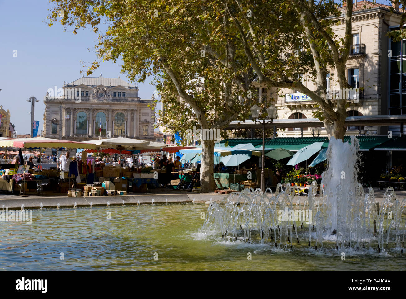 Fountain with market stalls in background, Place De La Comedie ...