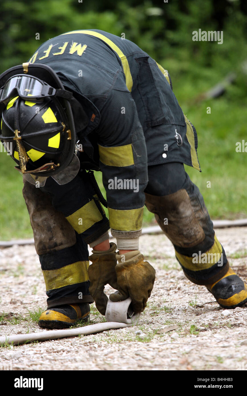 A firefighter rolling the hose after it being used at a scene Stock ...