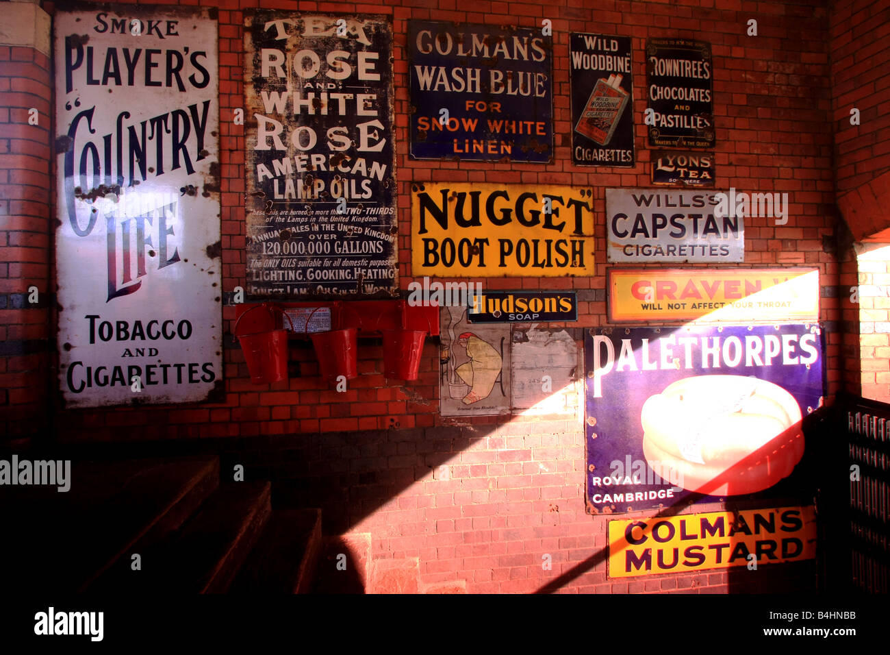 A collection of old enamel advertising signs on a brick wall Stock ...