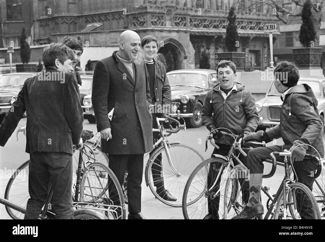 Actor Telly Savalas surrounded by young fans with bikes during a walk ...