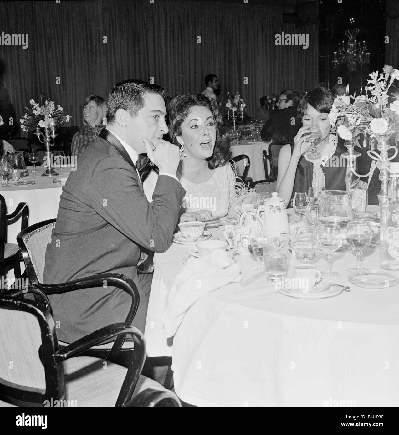 Elizabeth Taylor sitting on a dinner table with other people Liz Taylor ...