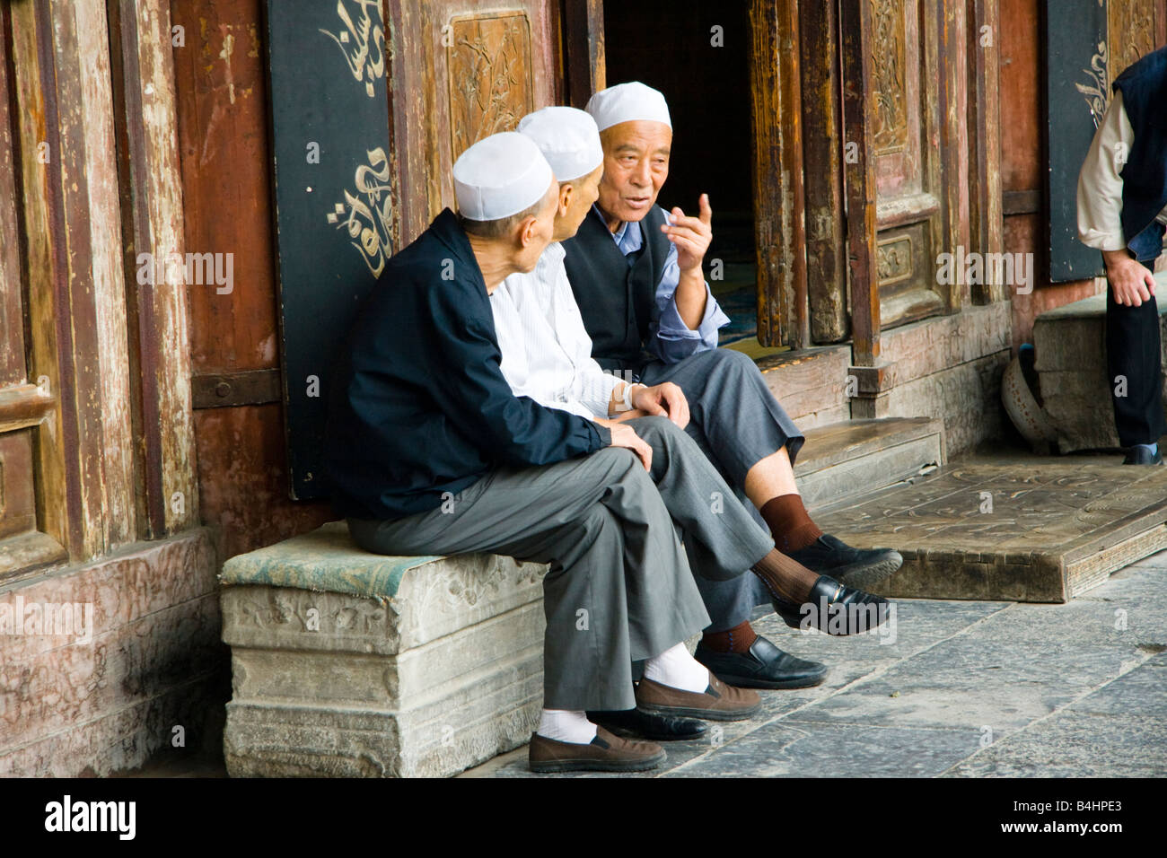 Chinese muslims sitting down outside talking in a mosque , Xian , China ...