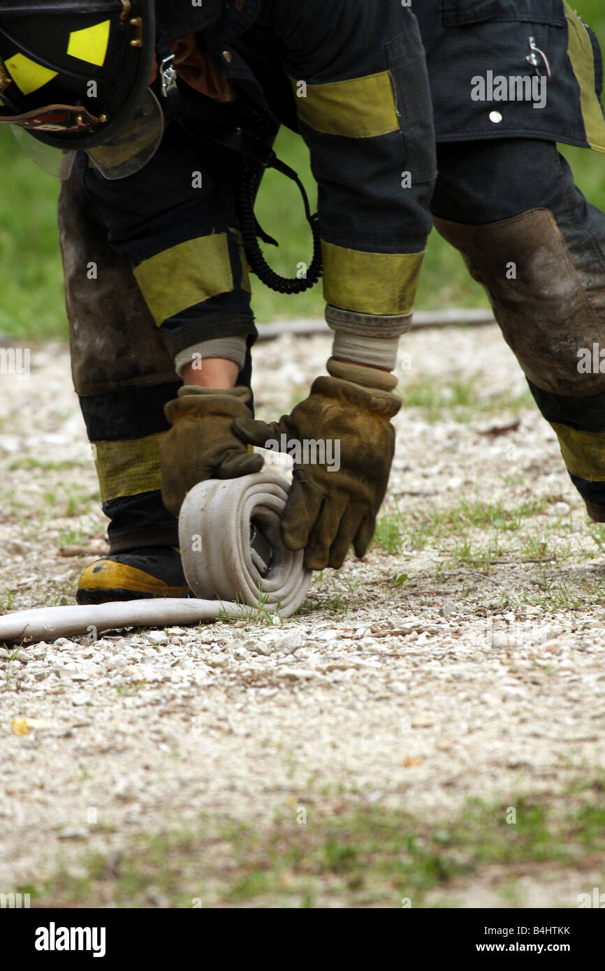 A firefighter rolling the hose after it being used at a scene Stock ...