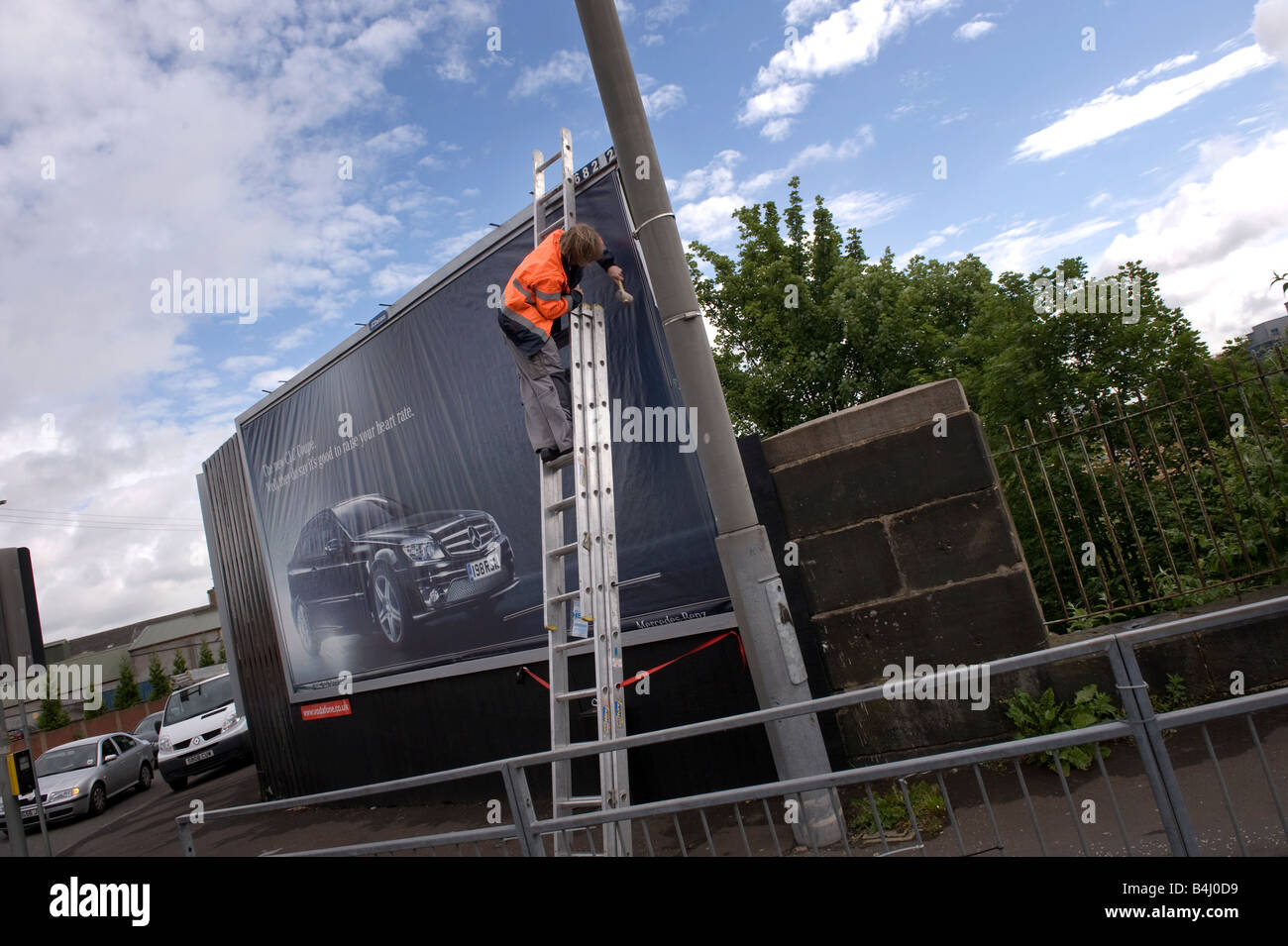 Man putting up a large billboard advertising poster at a busy road ...