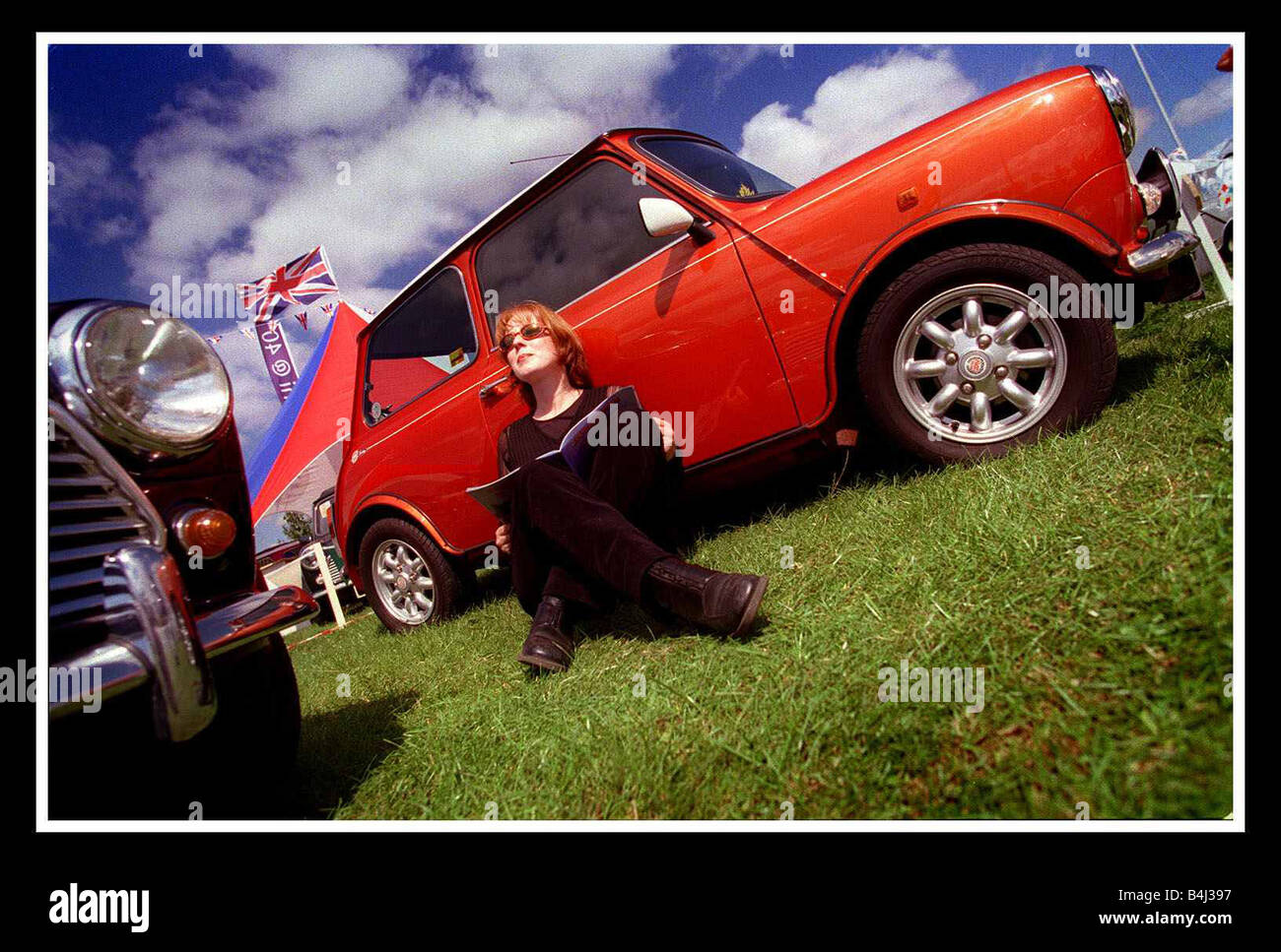 Mini car August 1999 Woman sitting leaning against red Mini in the sun ...