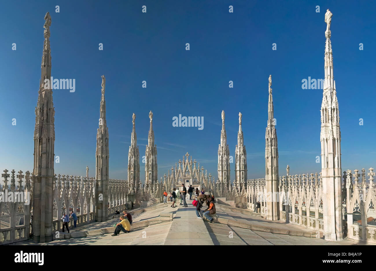 Top of the Milan Duomo with statues, roof and tourists Stock Photo - Alamy