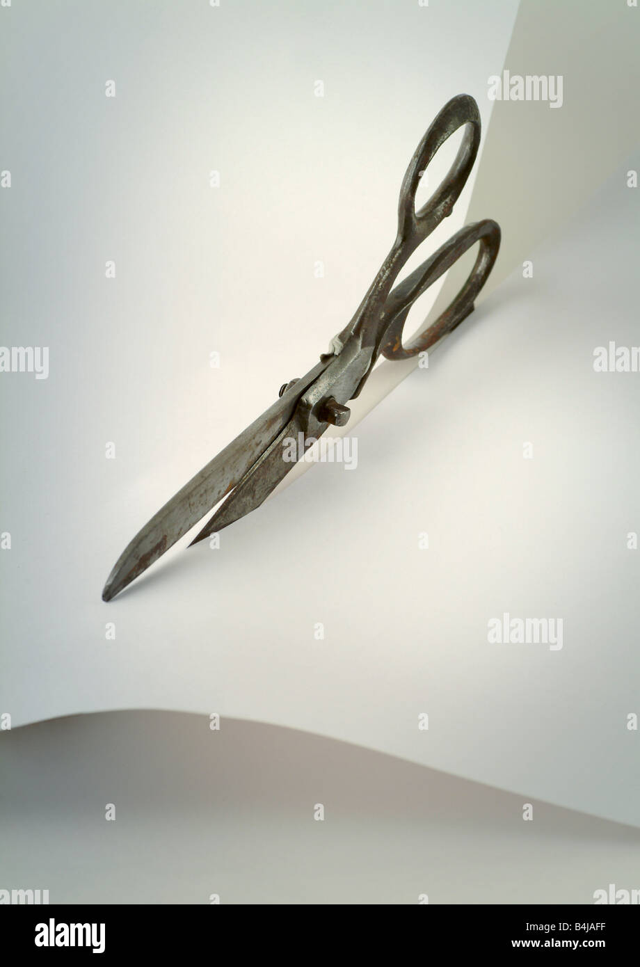 Pair of scissors cutting a sheet of paper Stock Photo - Alamy