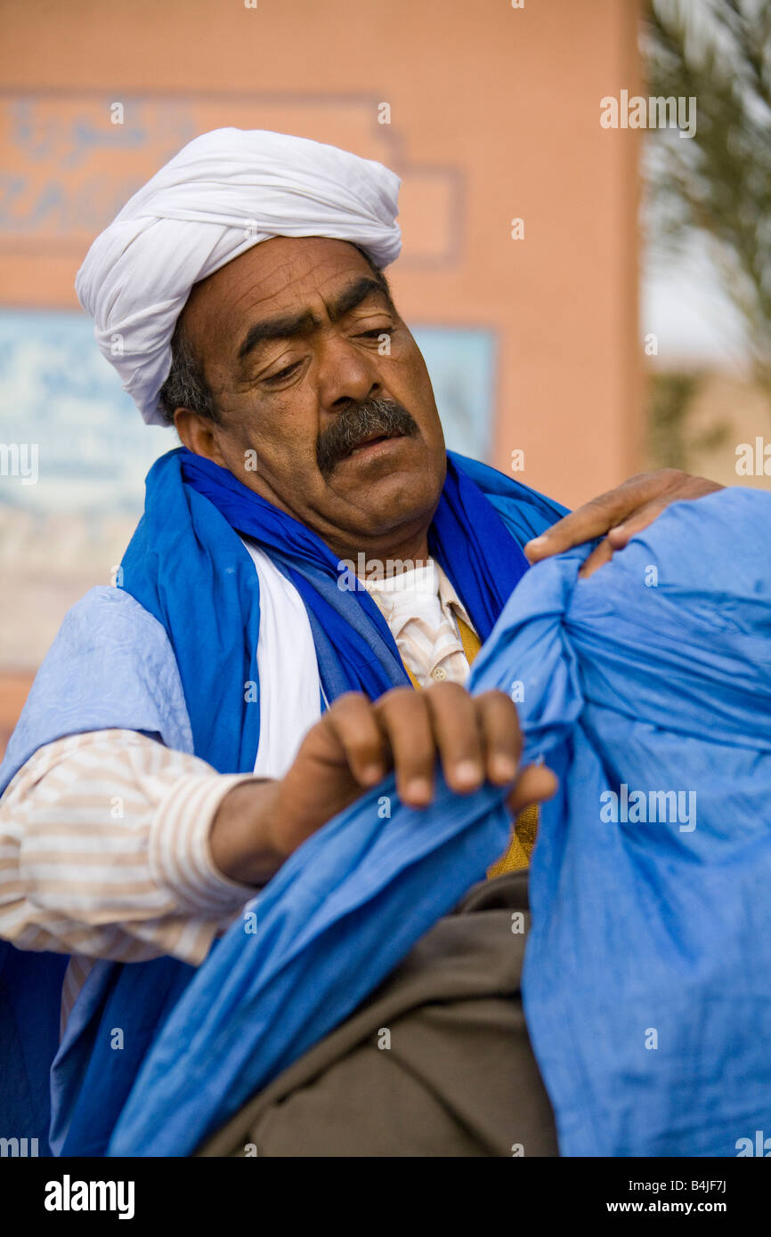 Merchant trader putting on head cover turban on tourist head Zagora ...