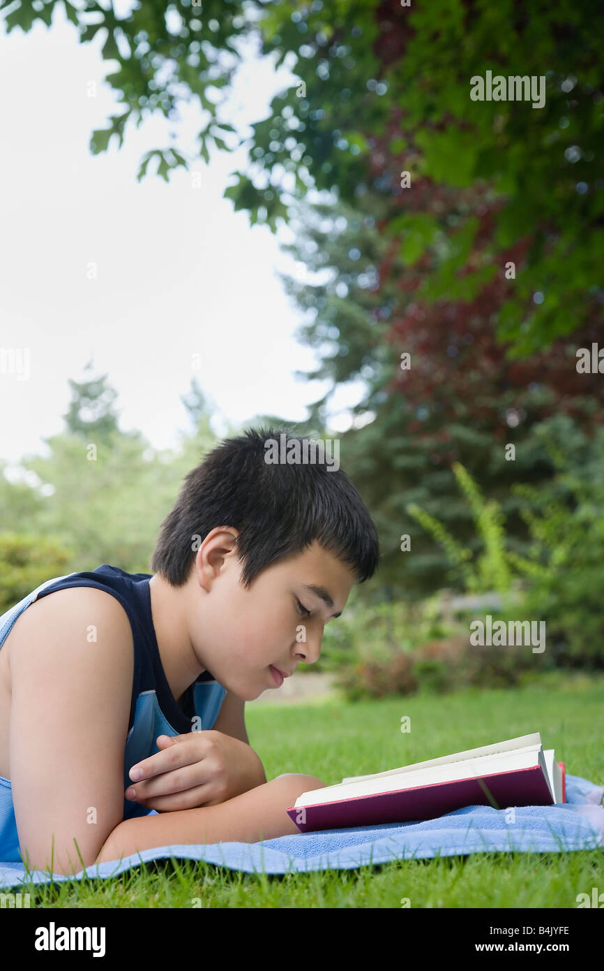 Asian boy reading in grass Stock Photo - Alamy
