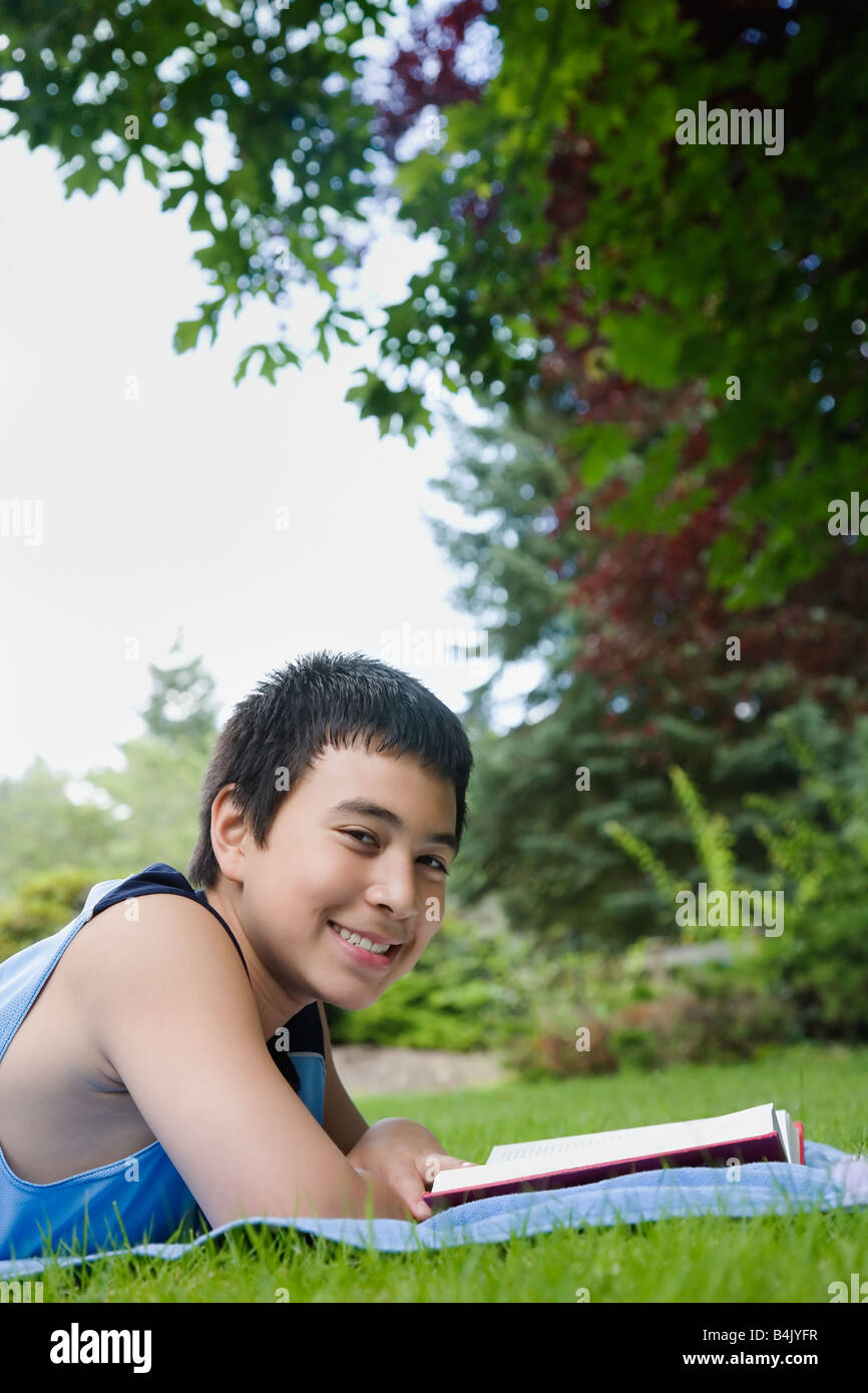 Asian boy reading in grass Stock Photo - Alamy