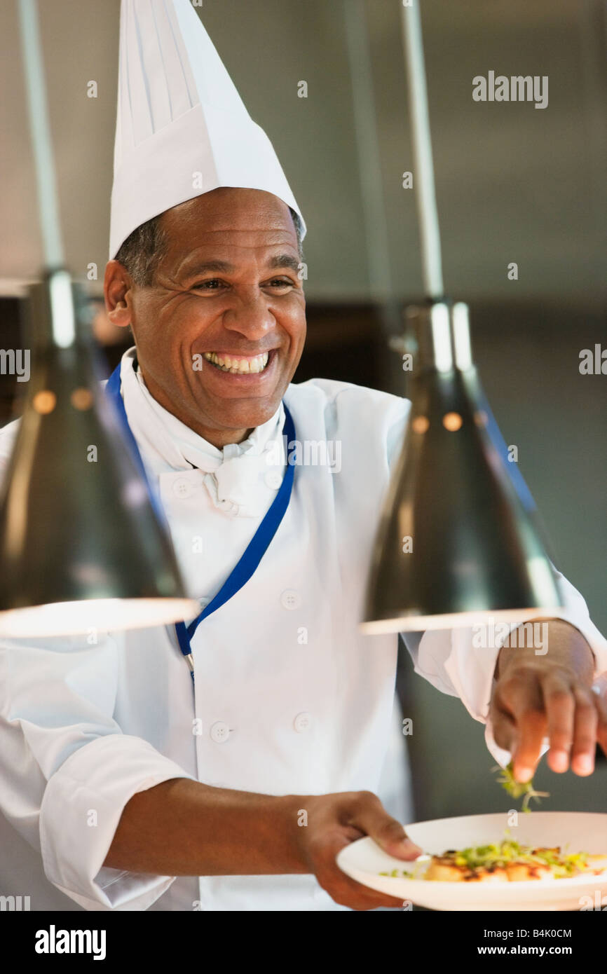 Mixed Race male chef garnishing plate of food Stock Photo - Alamy