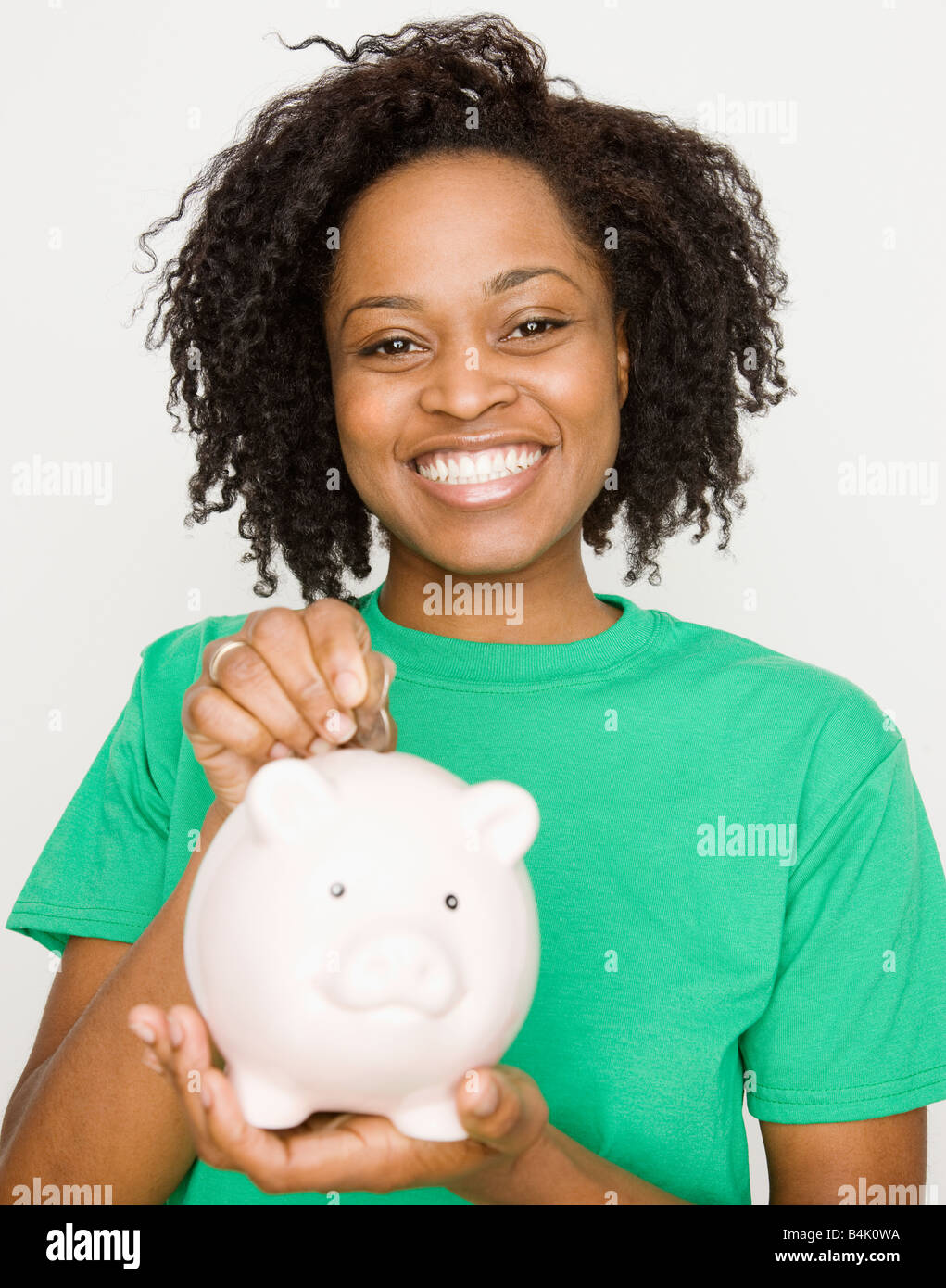 African woman putting coin in piggy bank Stock Photo - Alamy