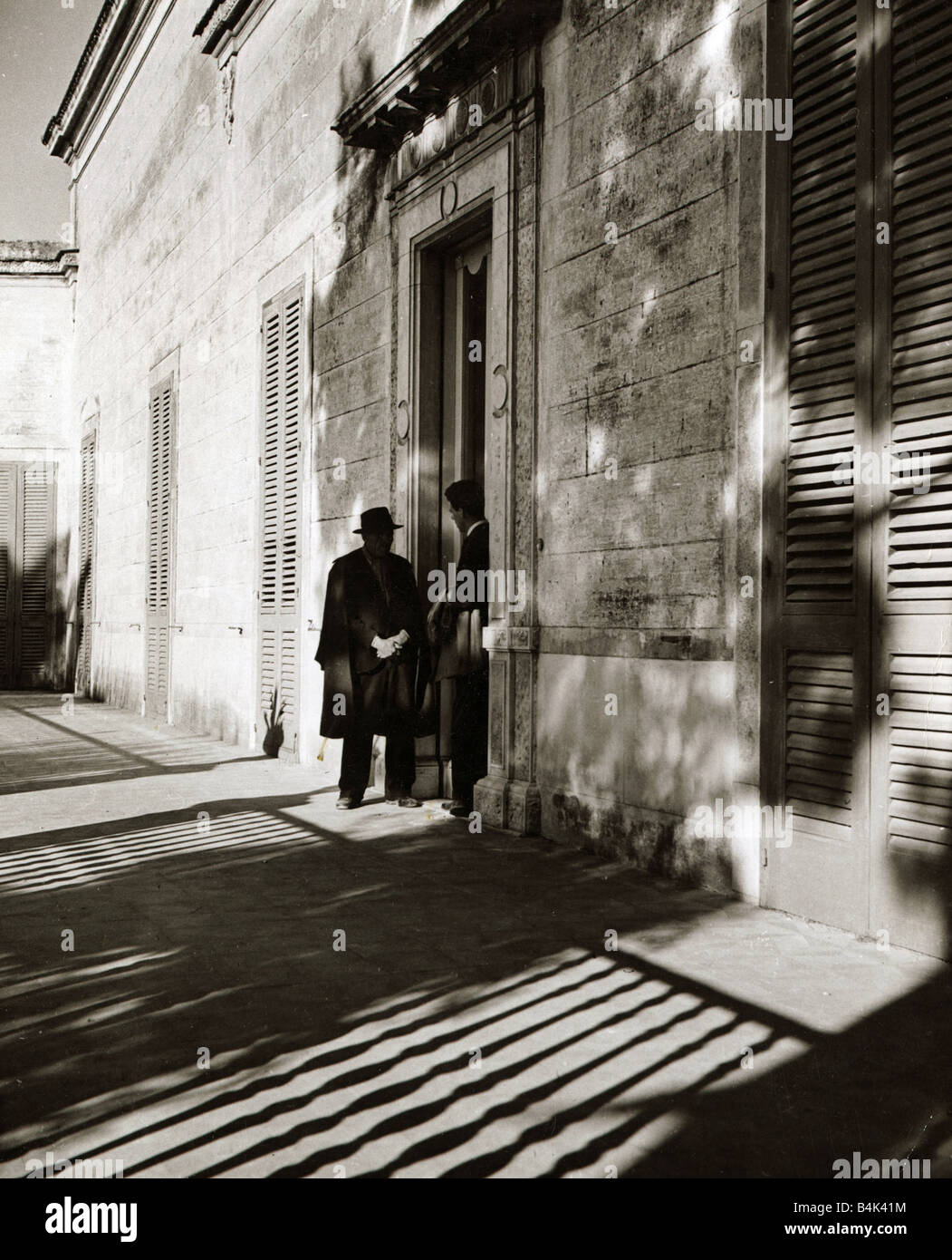Two local men talking on the street in Italy shadows casts circa 1950 ...